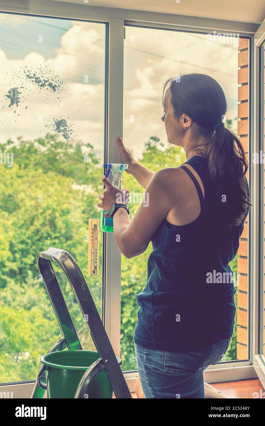 Back view of the young woman who washing the window with rag and window ...
