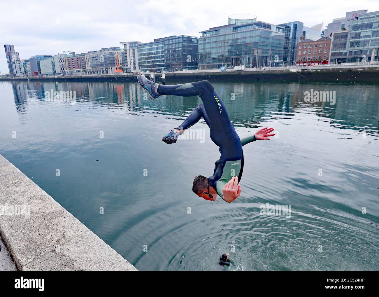Evan Burke jumps into the river Liffey in Dublin, as rain, wind and ...
