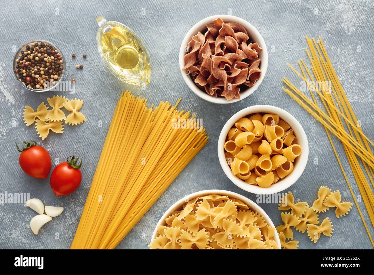 Variety of raw pasta in different types and shapes with tomatoes, oil ...