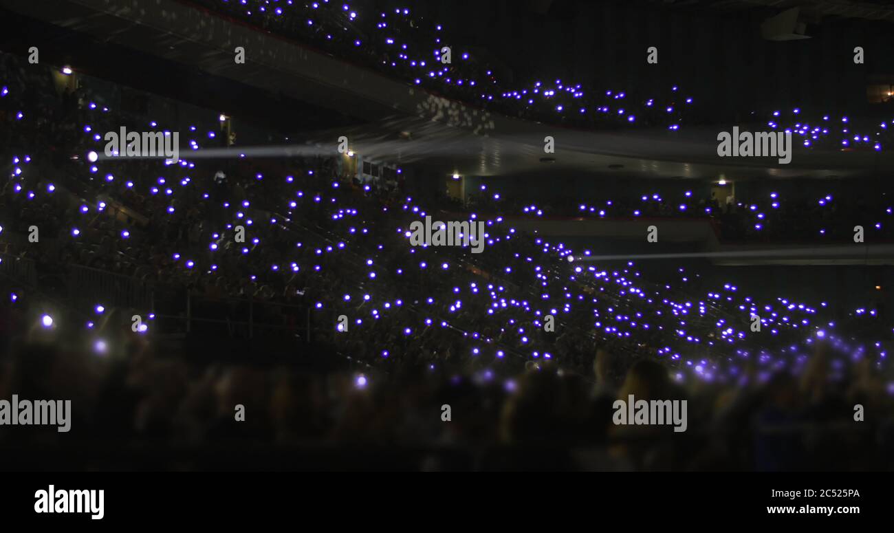Performance in the stadium at night. Crowd of people on stands waving ...