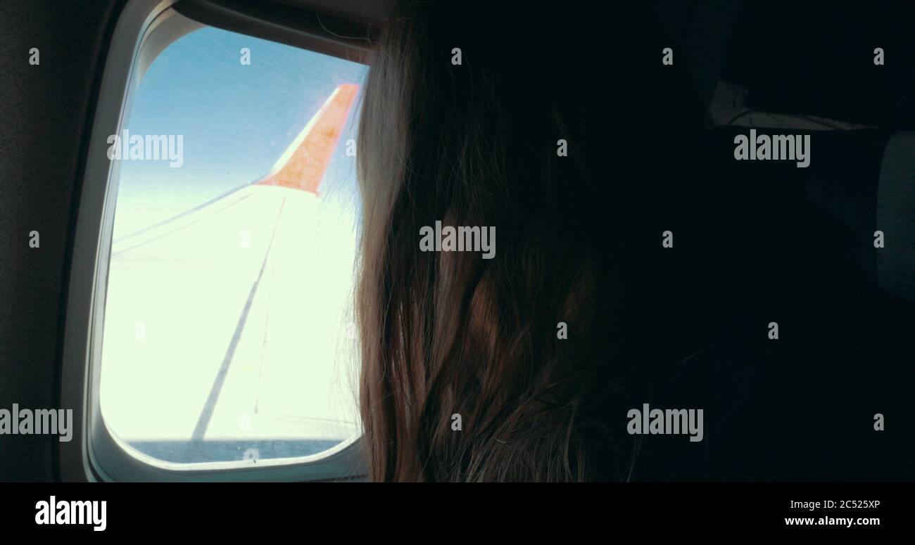 Woman passenger opening the blind and looking out the window of ...