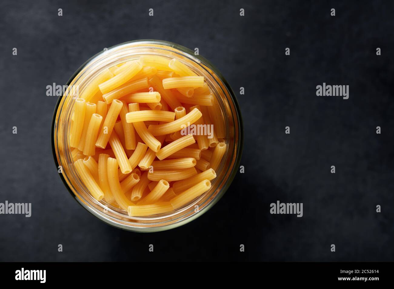 Ziti rigati or tubini pasta in a jar on black background with copy ...