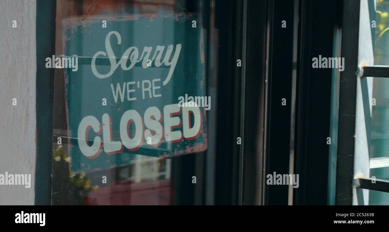 Dolly shot of a woman turning over shop-sign. Vintage style open sign ...
