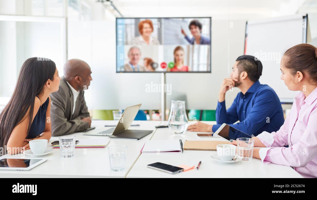 Digital video conference on monitor at business team meeting in ...