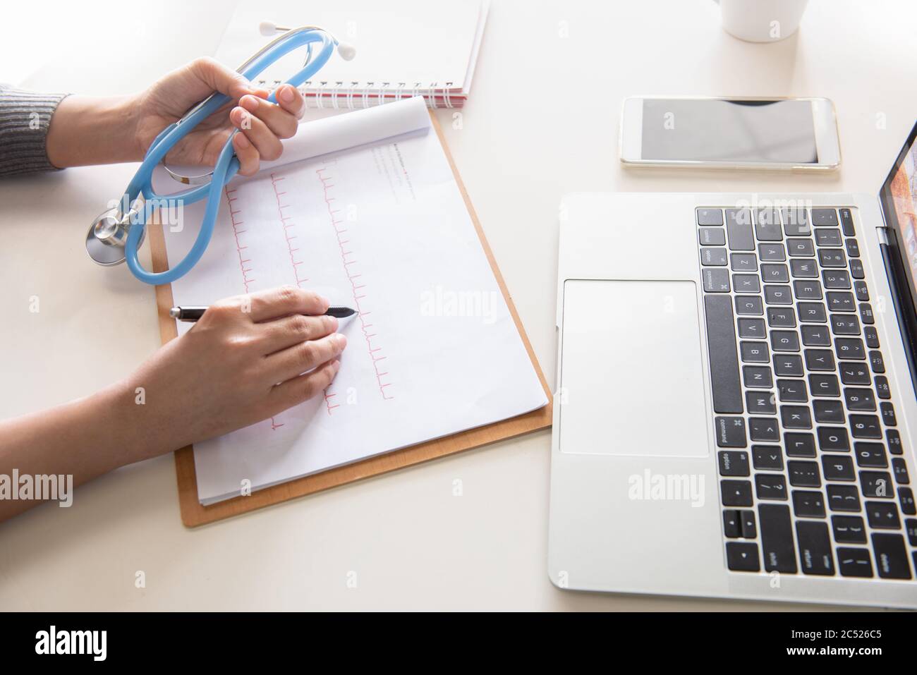 Close-up of doctor's hands writing prescription and holding stethoscope ...