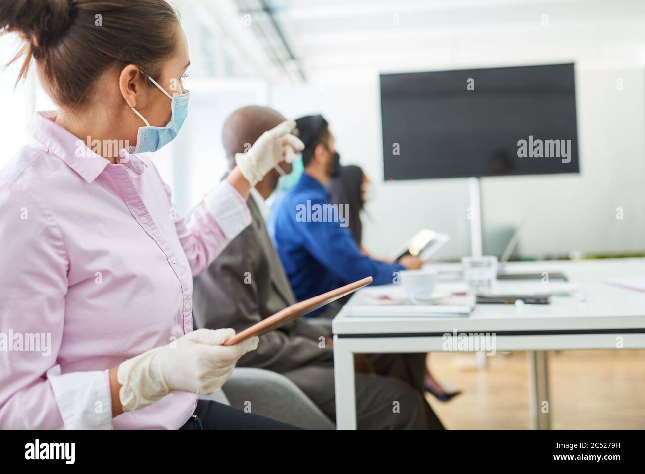Business people with face mask in a training or video conference ...