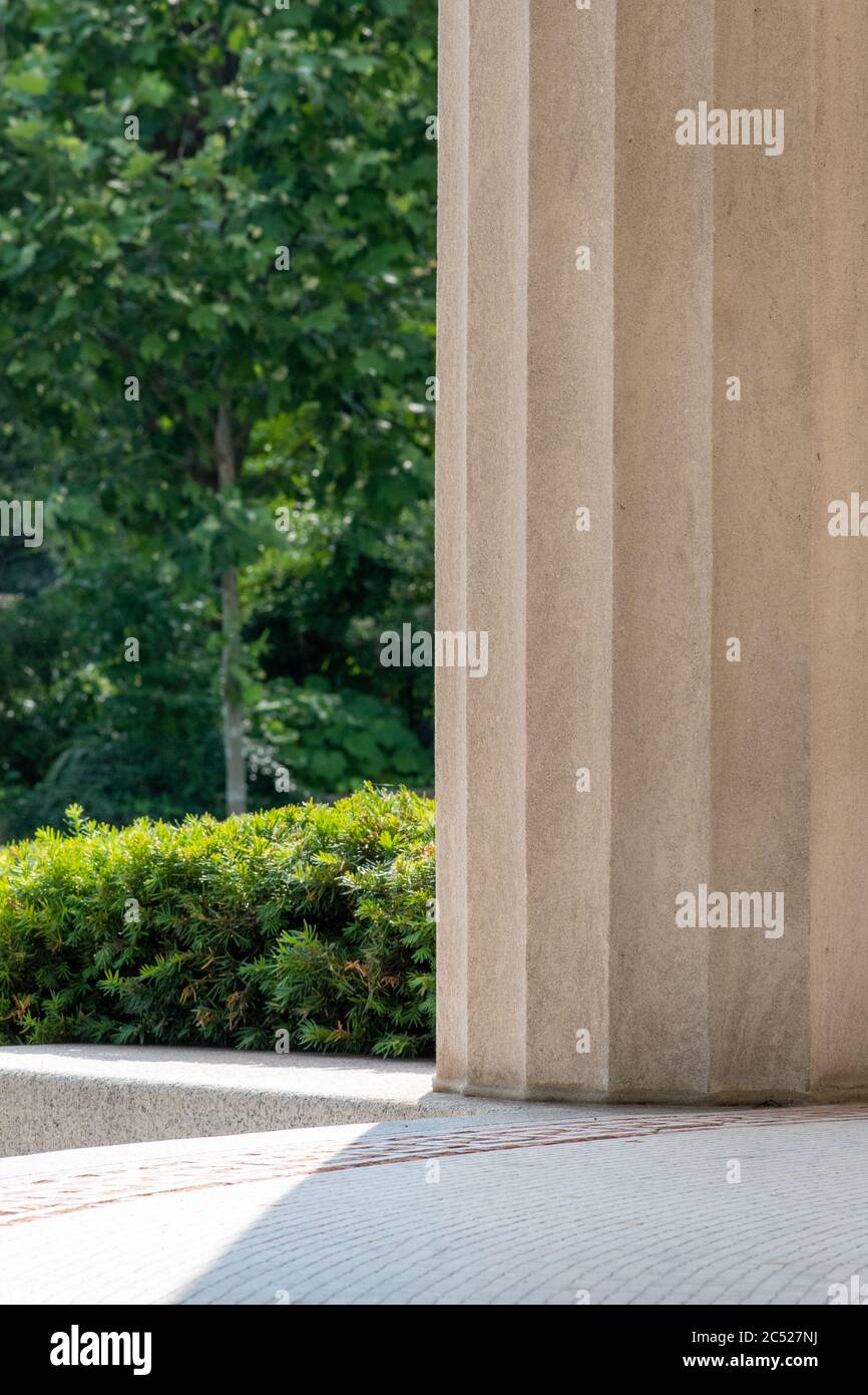 Isolated stone column architecture near a green park in the afternoon ...