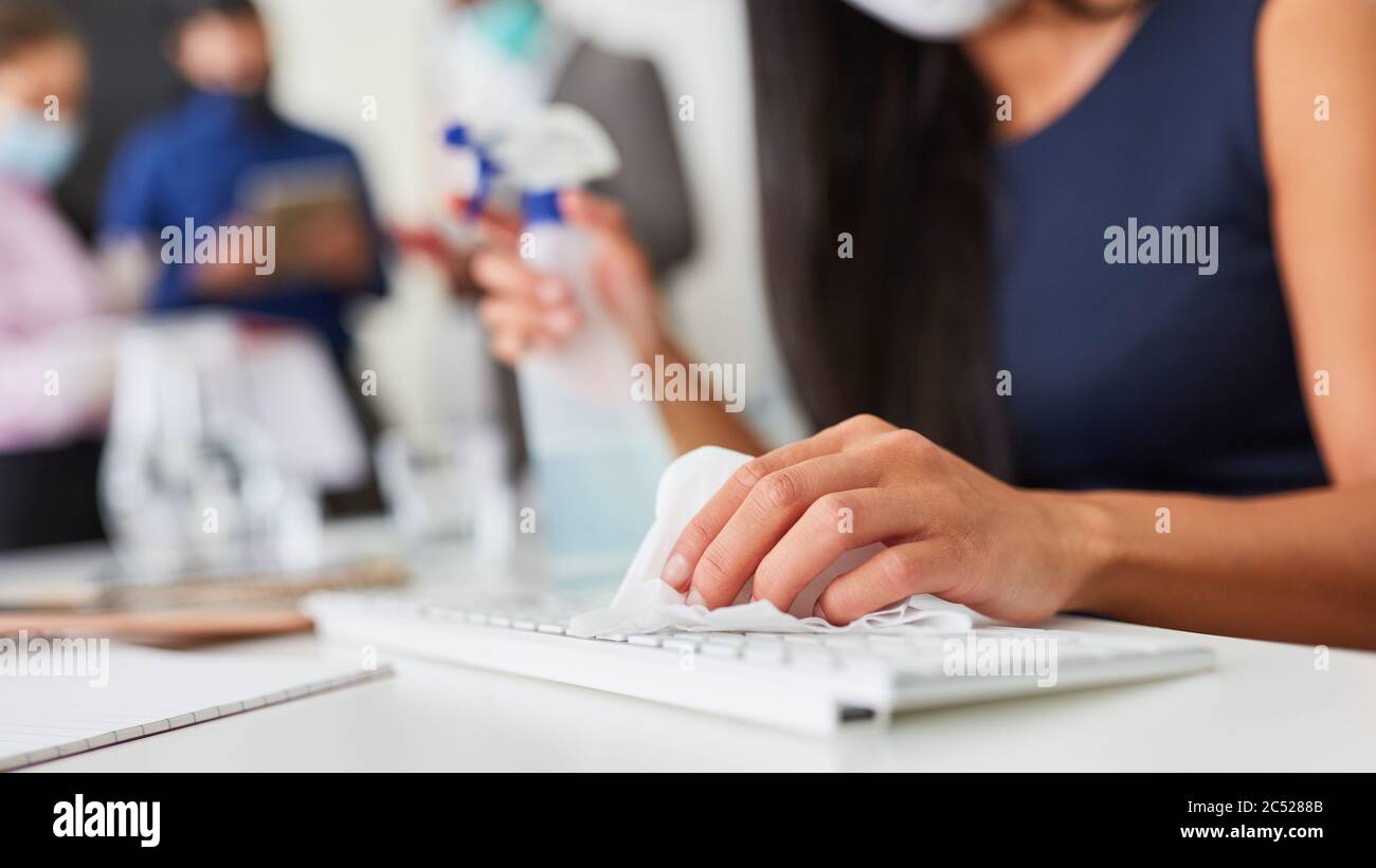 Businesswoman wearing mask at work in office while disinfecting ...