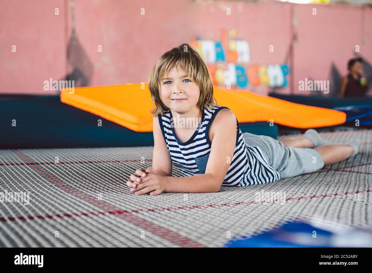 gymnast sitting on trampoline in fitness center. Tired child sits on ...