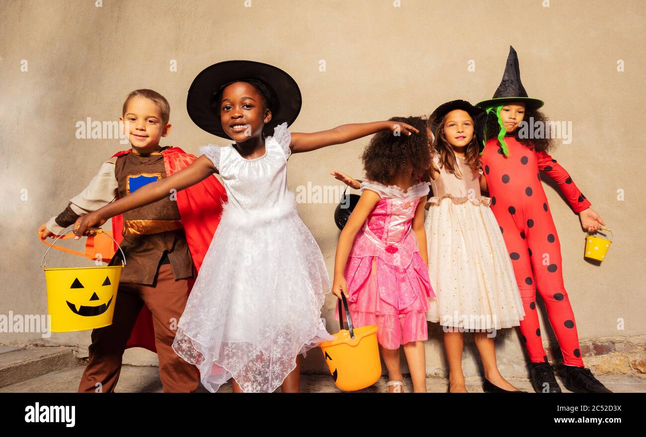 Girl with candy bucket over group of kids in Halloween costumes hug ...