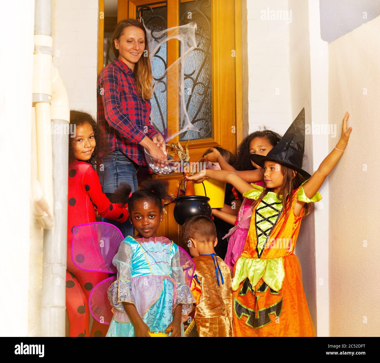 Halloween lifestyle scene with group of children in costumes receive ...