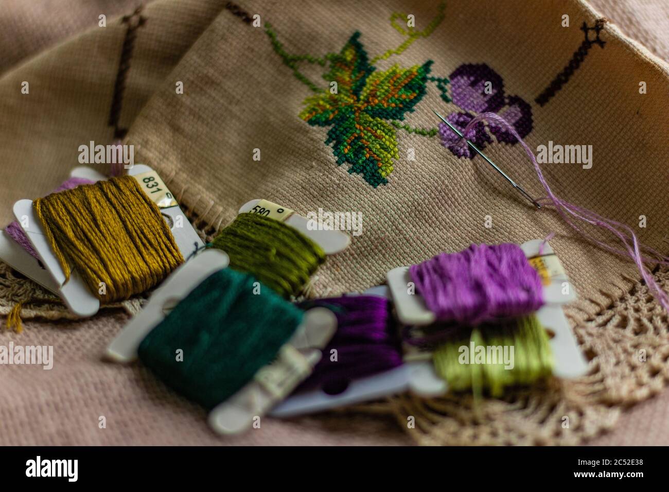 Closeup shot of colorful yarn rolls on a piece of fabric with cross ...