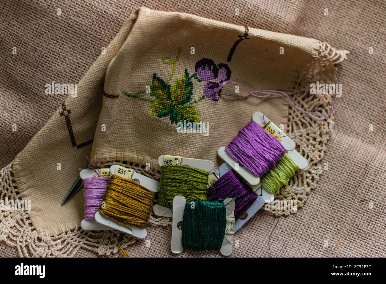 Closeup shot of colorful yarn rolls on a piece of fabric with cross ...