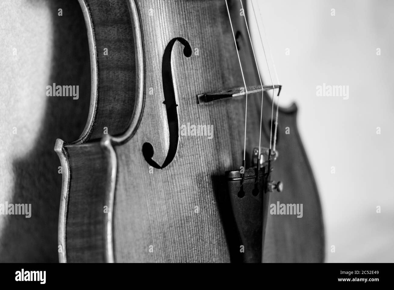 Vertical close up of violin f-hole, fine tuners, strings and bridge in ...