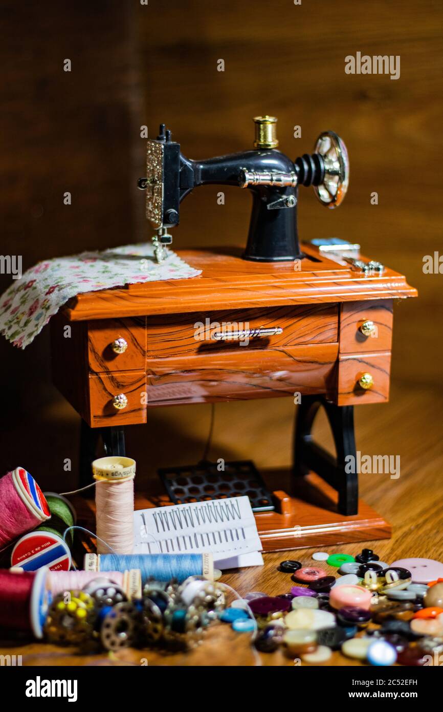 Toy sewing machine on the wooden table and colorful threads and buttons ...