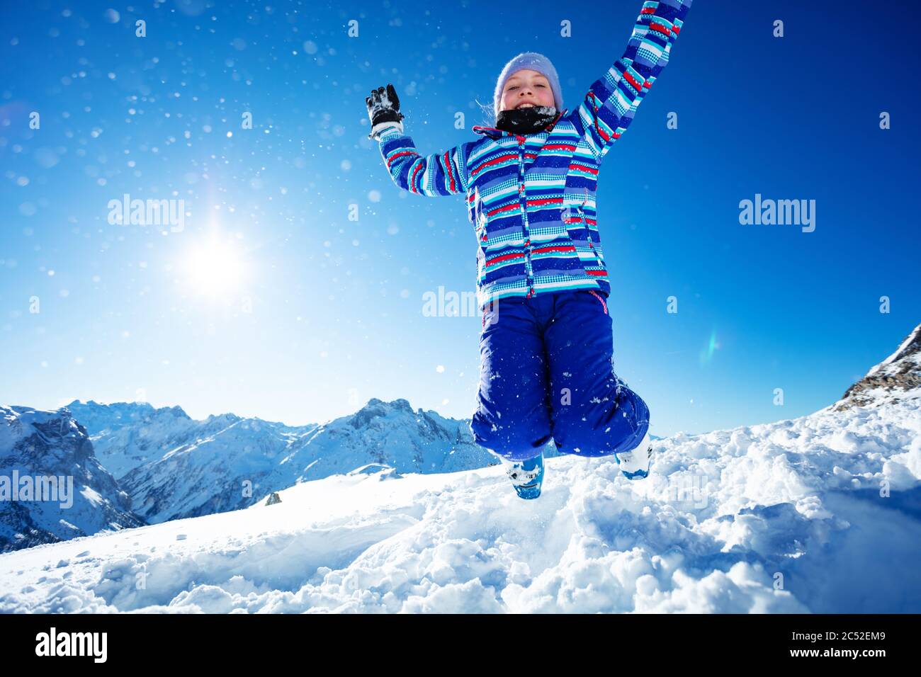 Cute motion action portrait of young ski girl jump in mid-air and throw ...