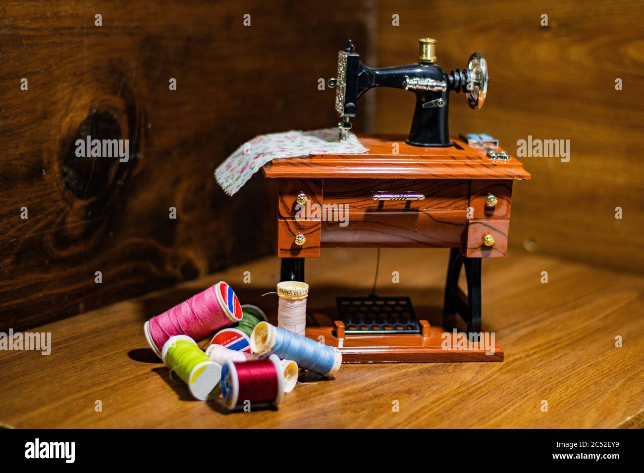 Mini sewing machine on a wooden table with small colorful threads next ...