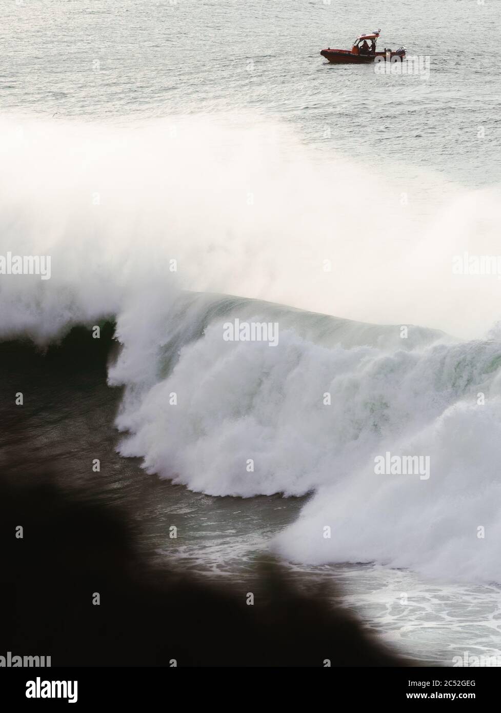 Vertical shot of restless sea scenery with lofty waves and a boat on ...