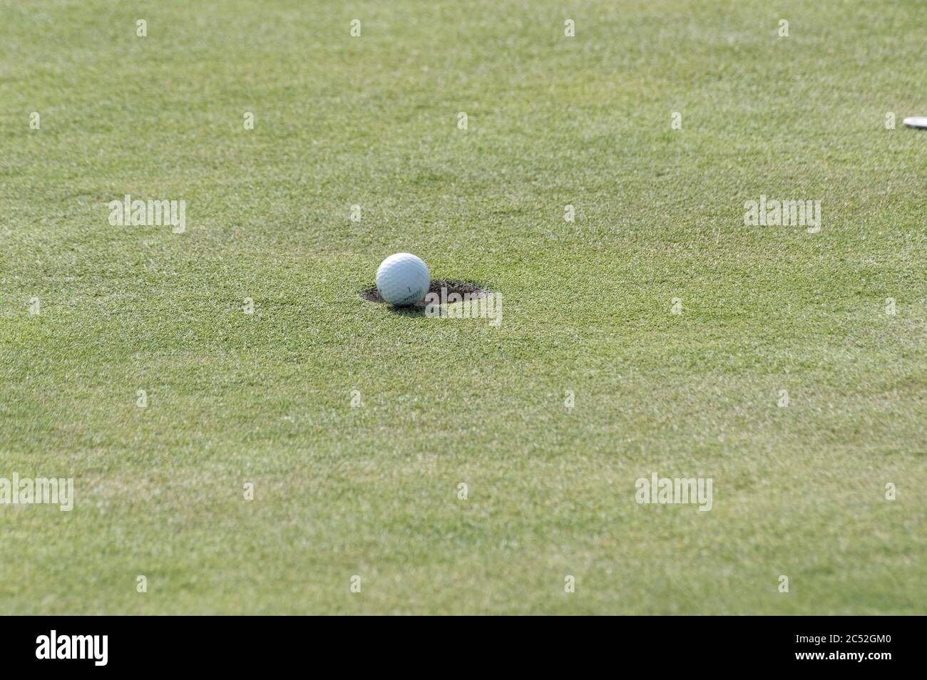 Golf ball on the grass with a few centimeters left to fall into the ...