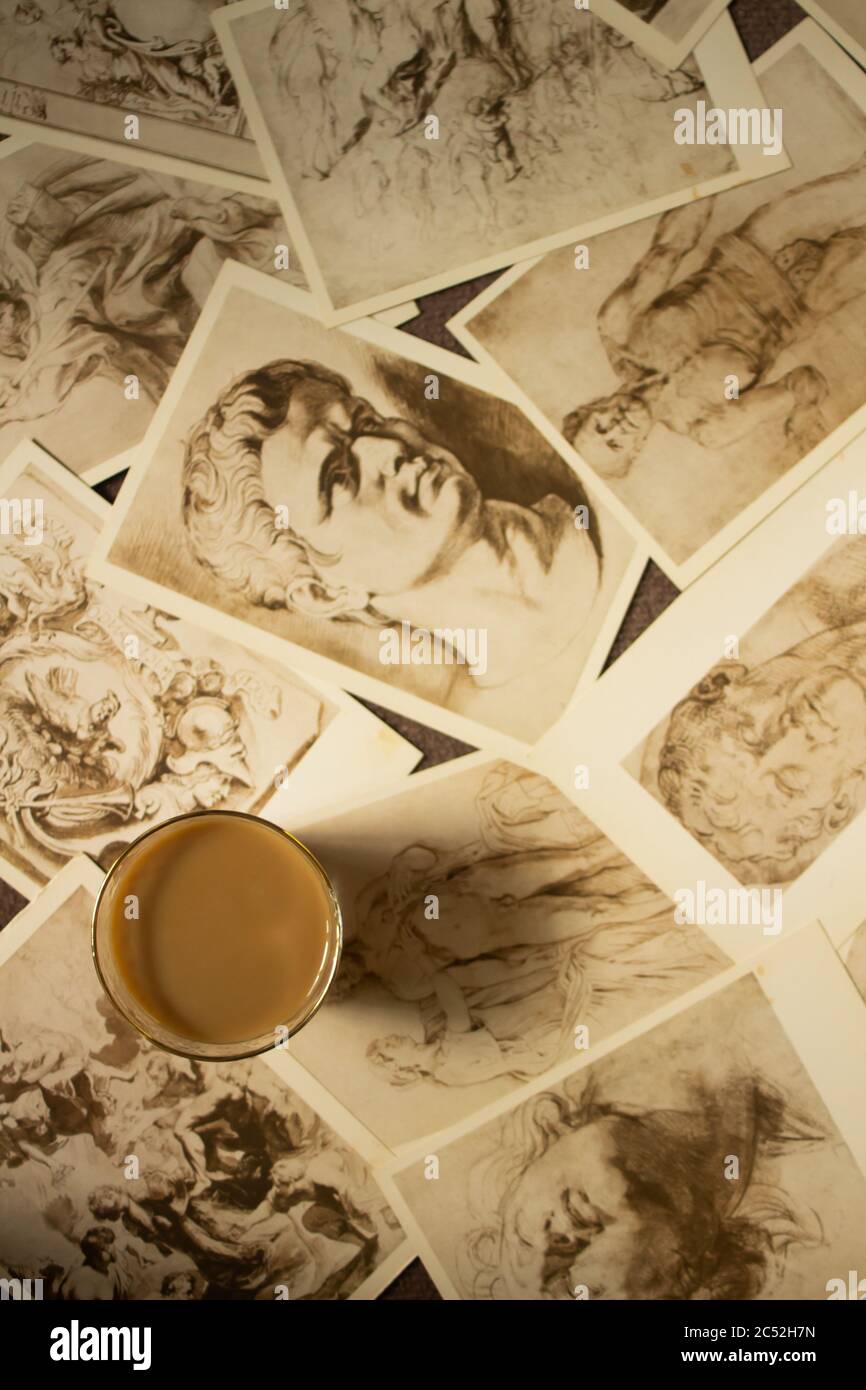 Old postcards are scattered in a chaotic manner and a cup lies on them ...