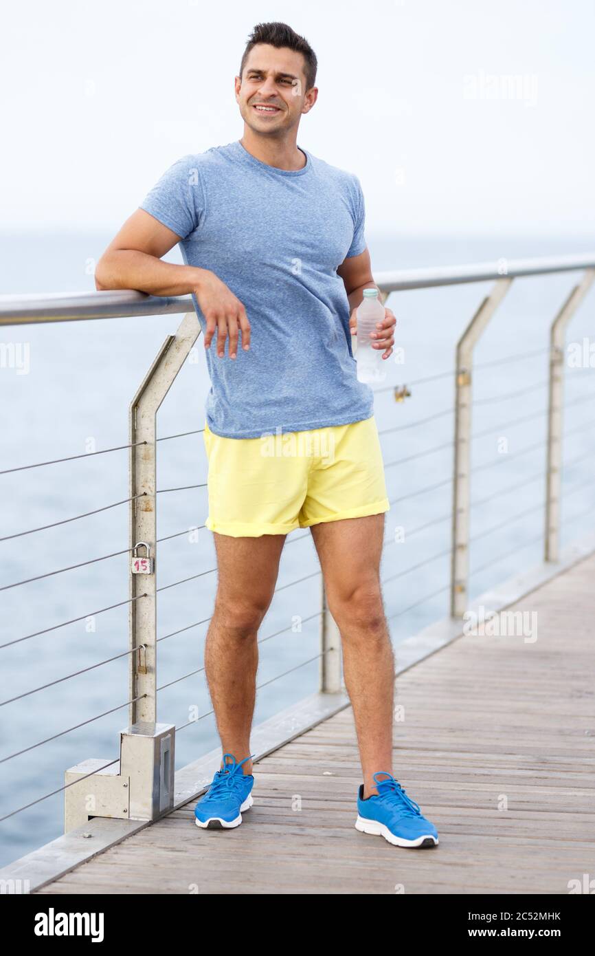 Athletic man with fit body relaxing after outdoor training with bottle ...
