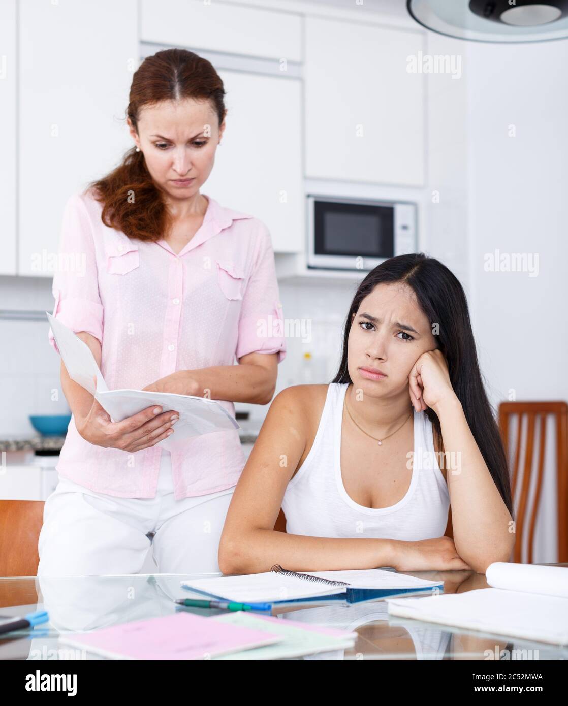 Mother and daughter in the kitchen, mother is not happy with grades of ...