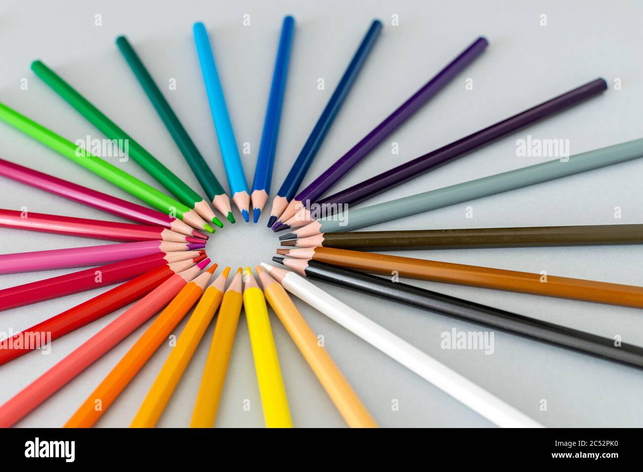 a small spectrum of colourful pencils placed on a table in a circle ...