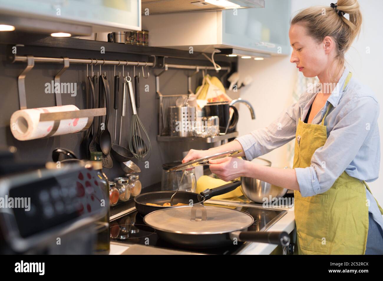 Stay at home housewife woman cooking in kitchen, stir frying dish in a ...