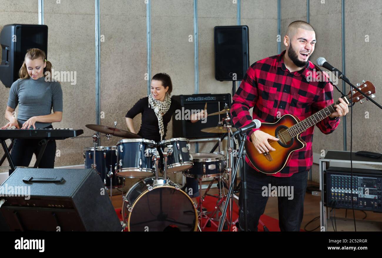 Bearded guy soloist playing a guitar and singing with two girls of his ...