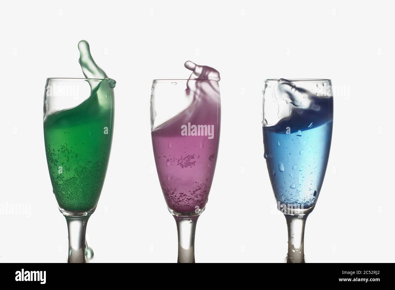 Three multi coloured cocktails splashing about Stock Photo - Alamy