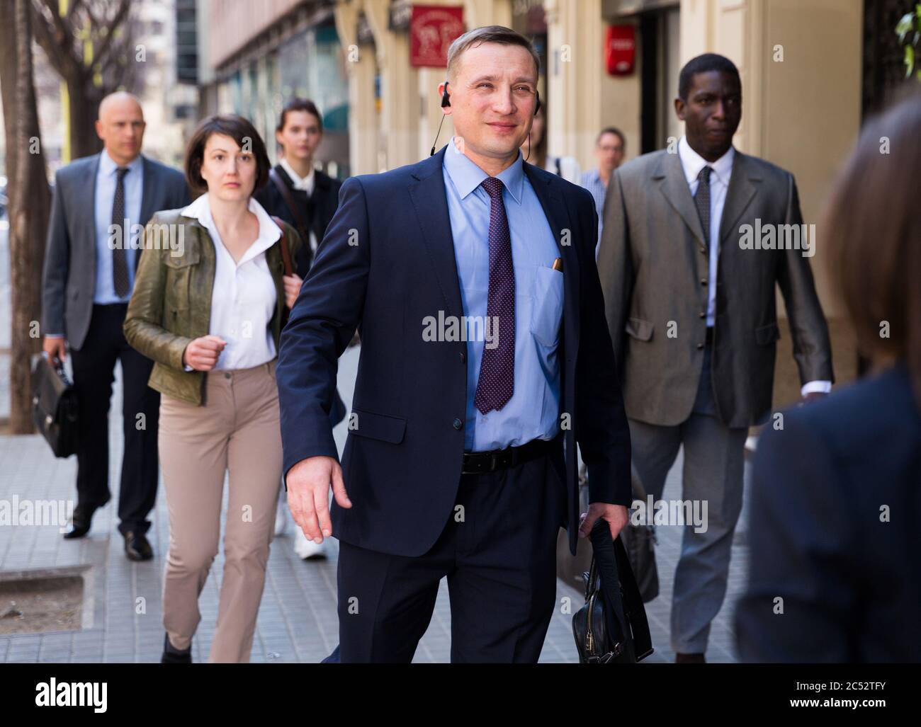 Focused business man with briefcase in hand walking on city street in ...