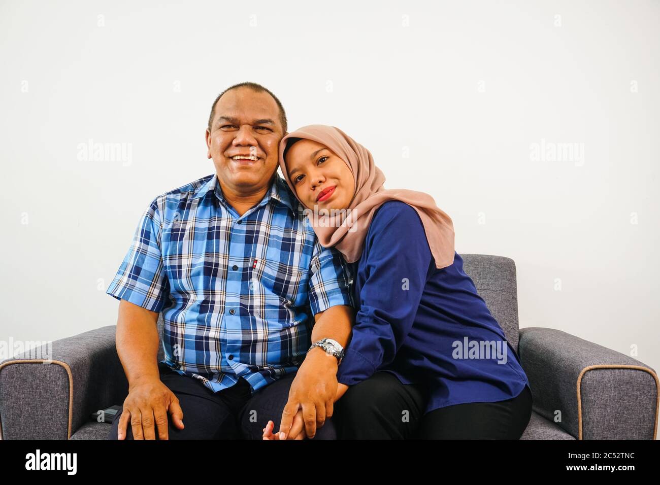 Senior Citizen cudling with his granddaughter on a sofa. Family Bonding ...