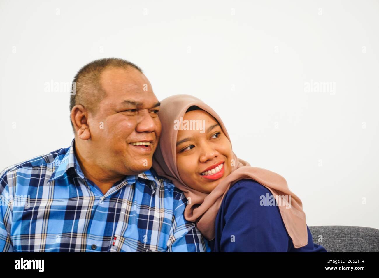 Senior Citizen cudling with his granddaughter on a sofa. Family Bonding ...