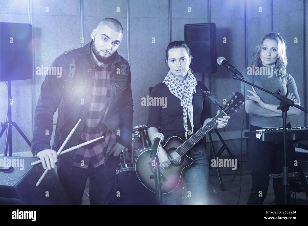 Three happy smiling bandmates posing together with musical instruments ...