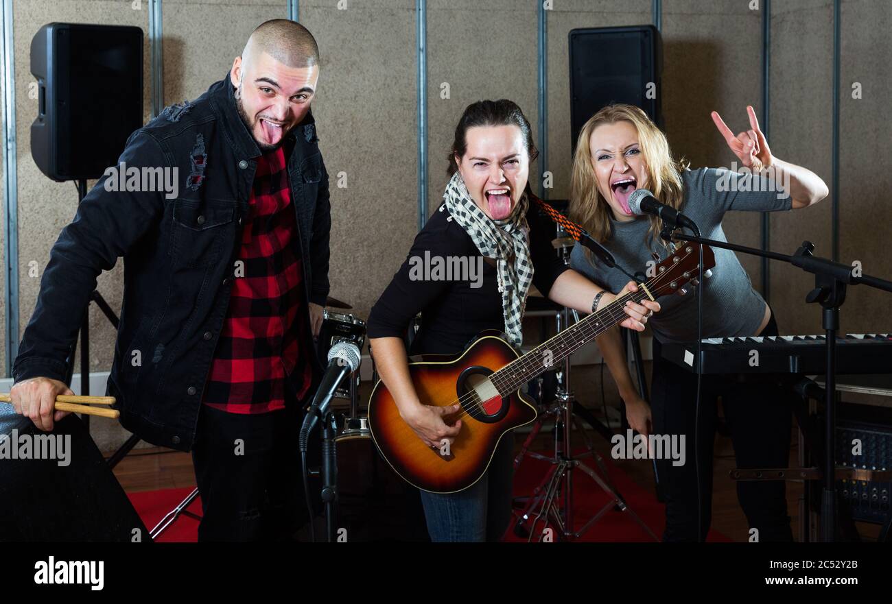 Expressive adult group of rock musicians posing with instruments in ...