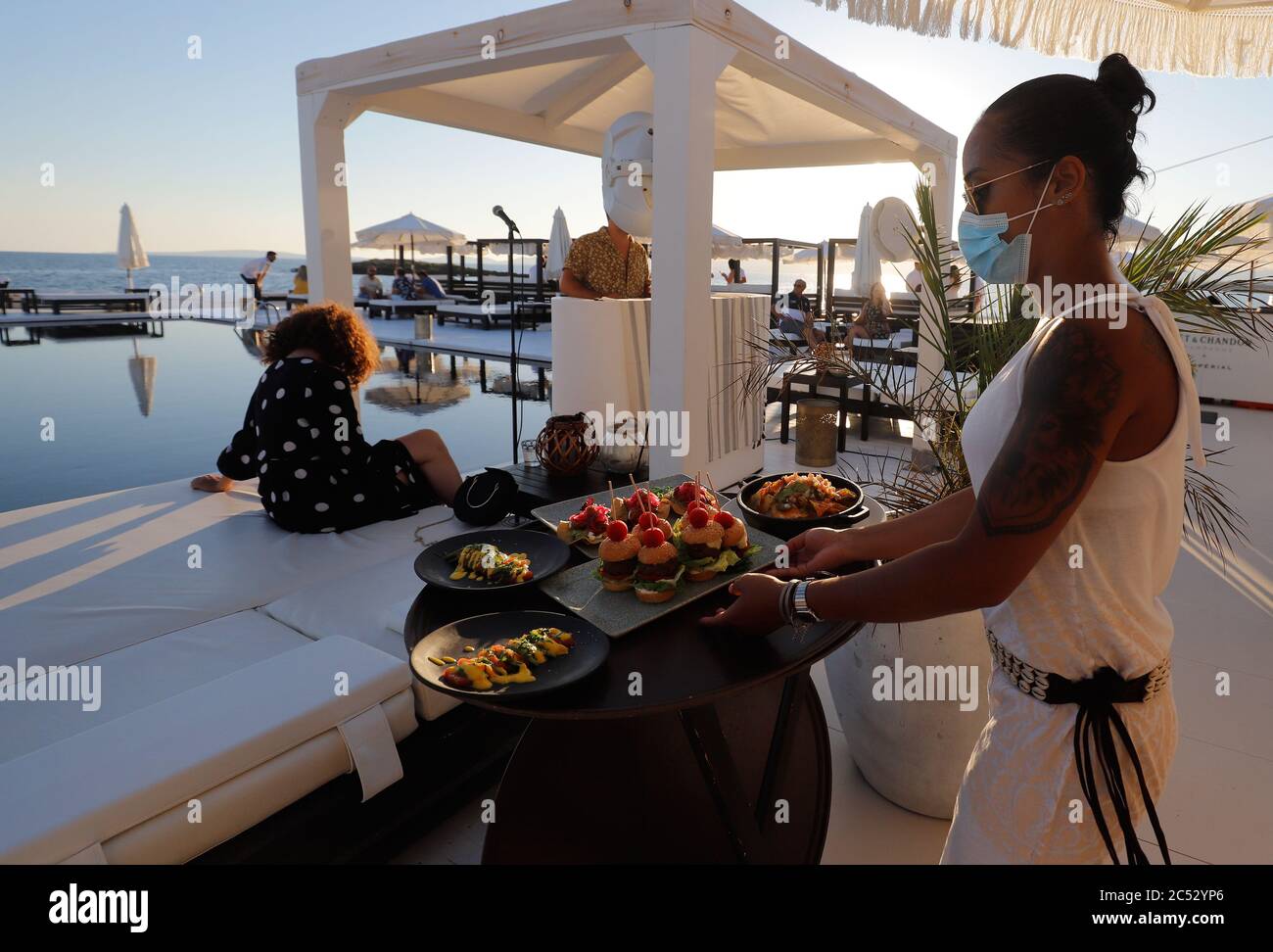 Palma, Spain. 23rd June, 2020. A waitress with a face mask serves the customers of the Bar ...