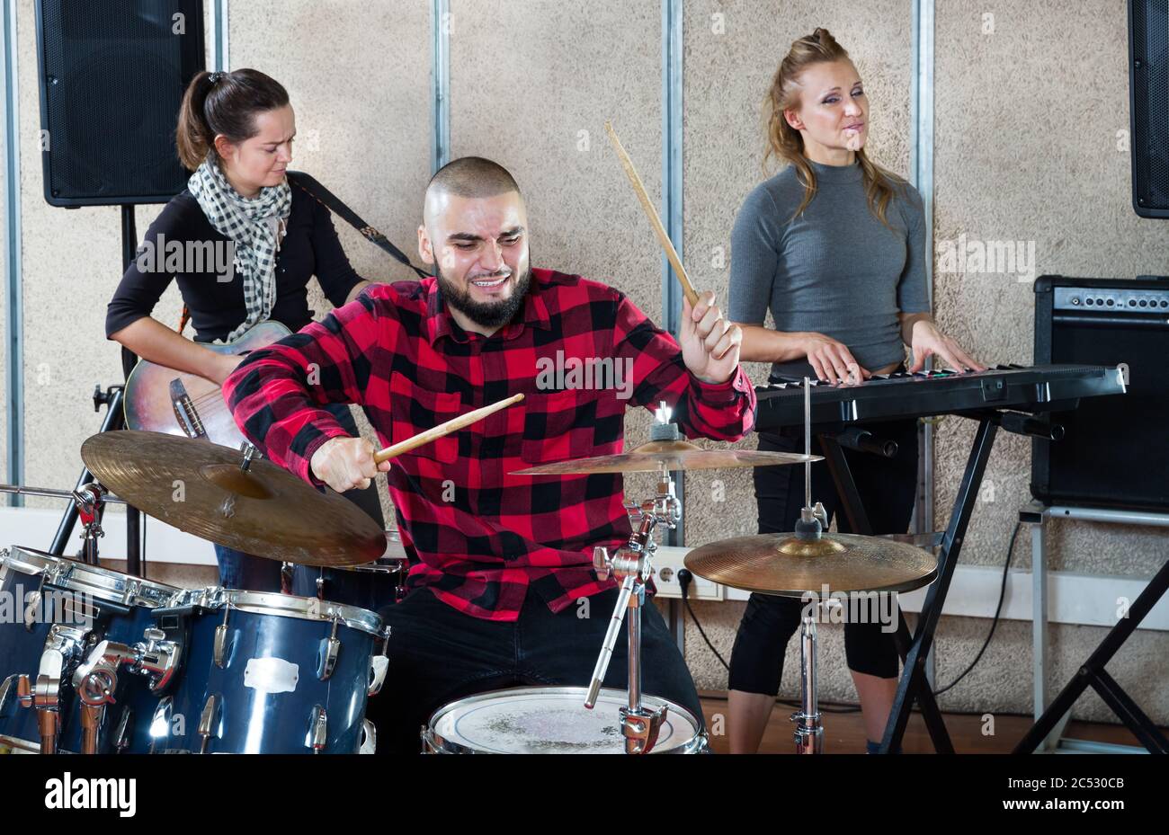 Rehearsal of music group. Rock band with emotional male drummer playing ...