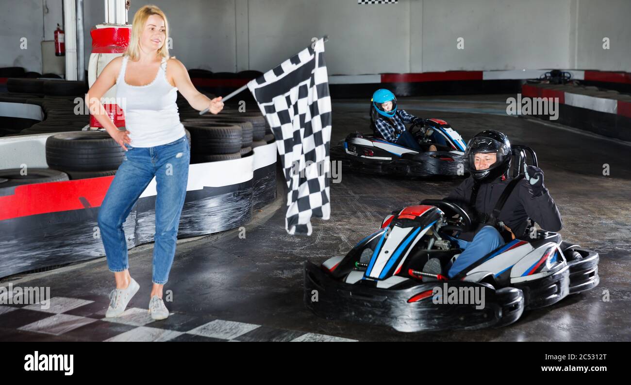 Portrait of male racer in helmet crossing finish line on a kart track ...