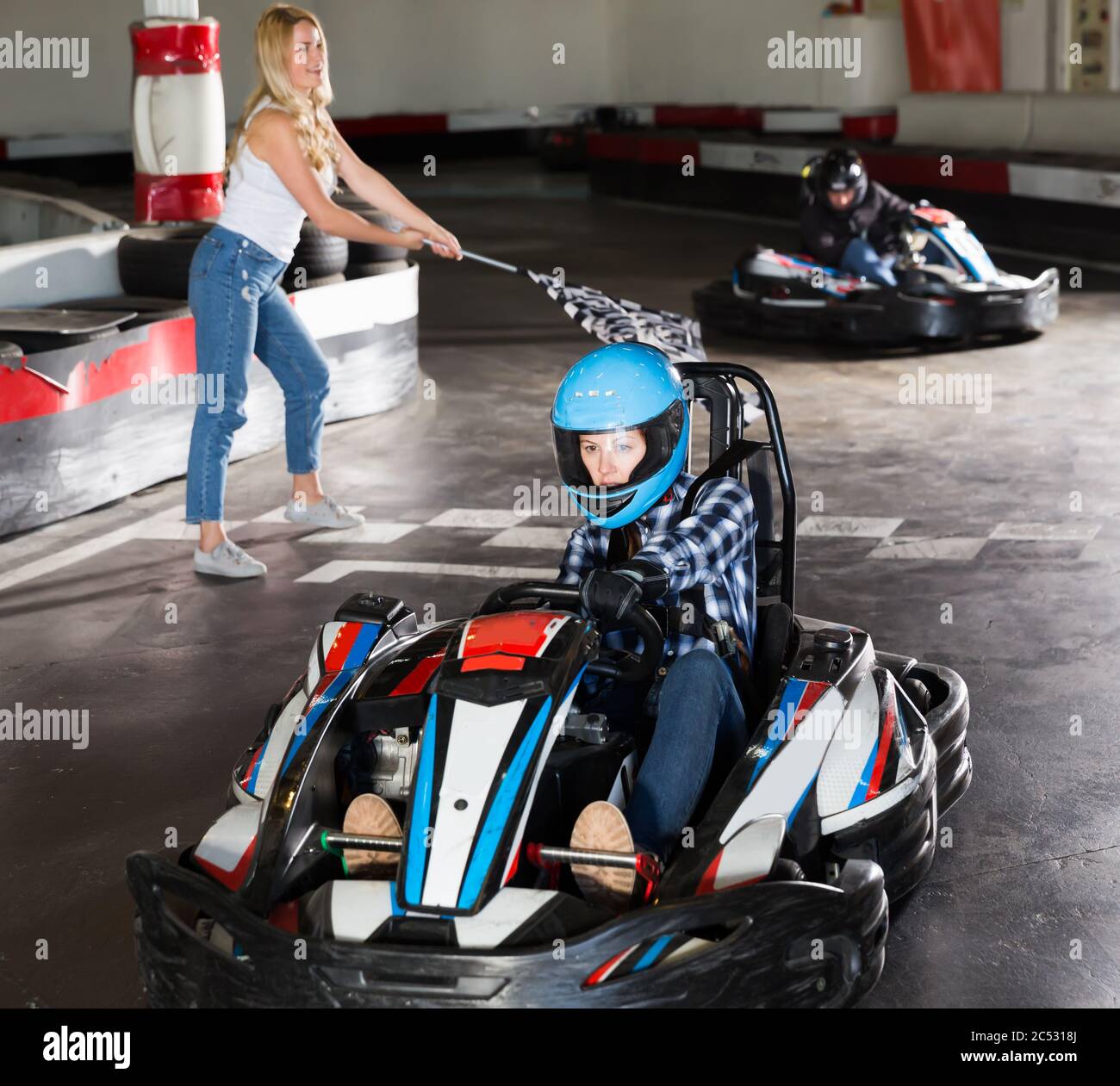 Smiling adult female go-cart racer crossing finish line Stock Photo - Alamy