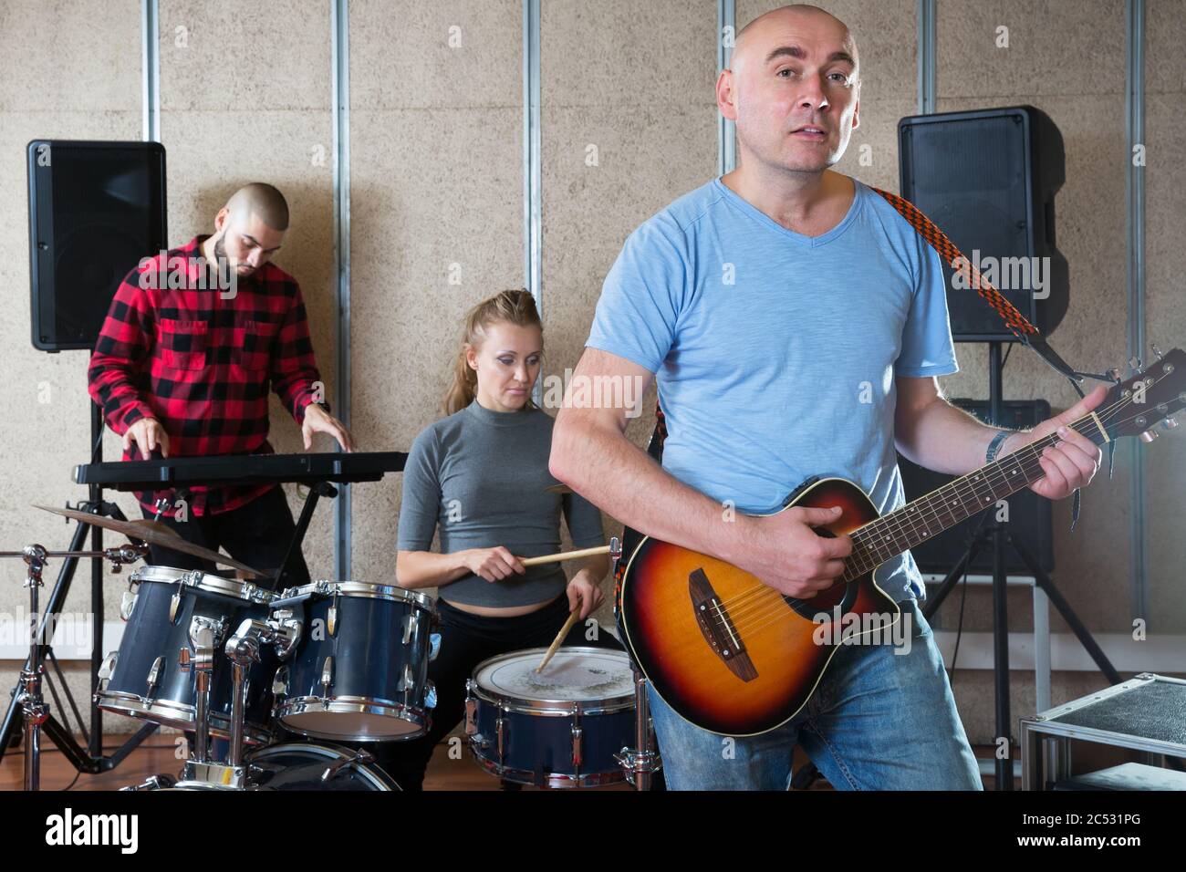 Male soloist playing guitar and singing with music band members in ...