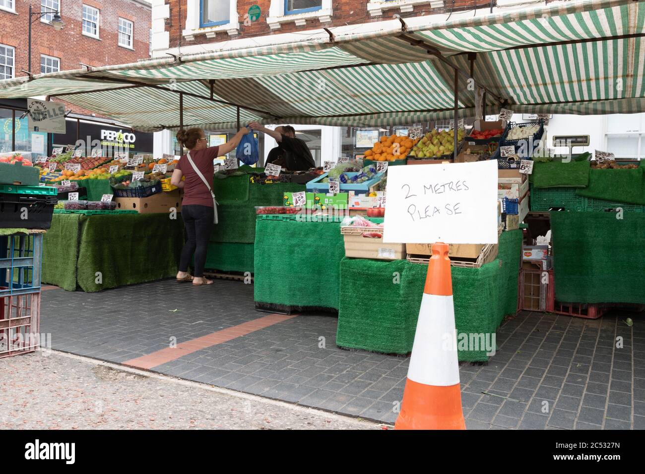 Fruit and vegetable market stall with sign asking the public to keep ...