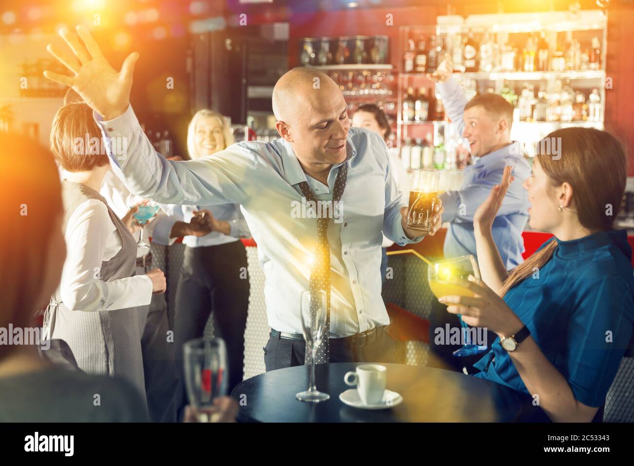 Man in unbuttoned shirt and untied tie drinking alcohol and having fun ...