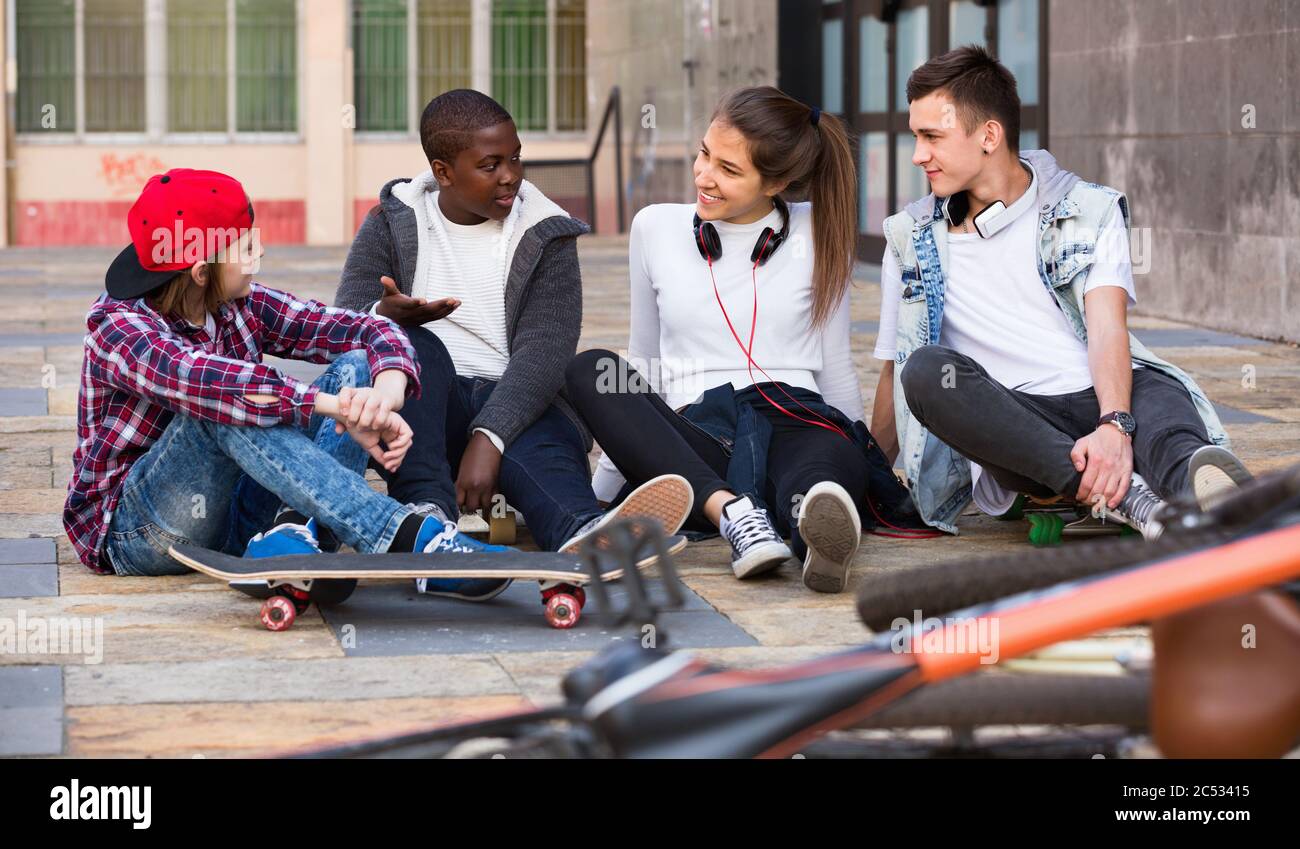 Group of ordinary positive teenage friends relaxing and chatting in ...