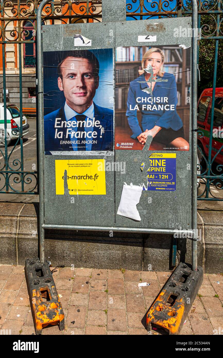 Partially torn election posters of Emmanuel Macron (en marche) and ...
