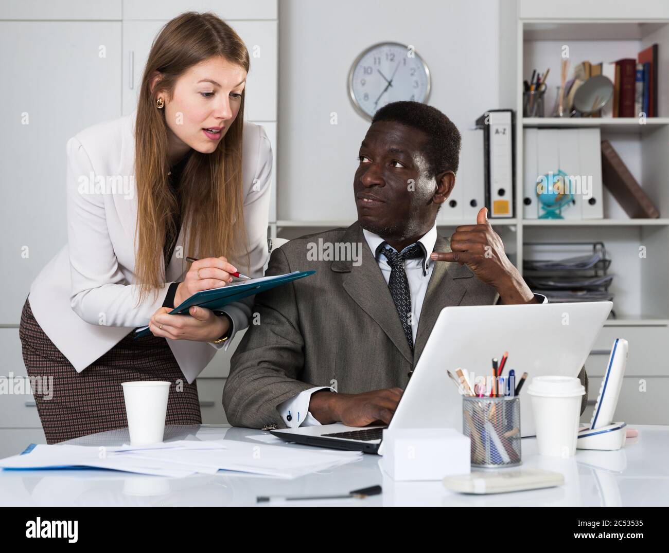 Young woman assistant and man manager working with laptop and papers in ...