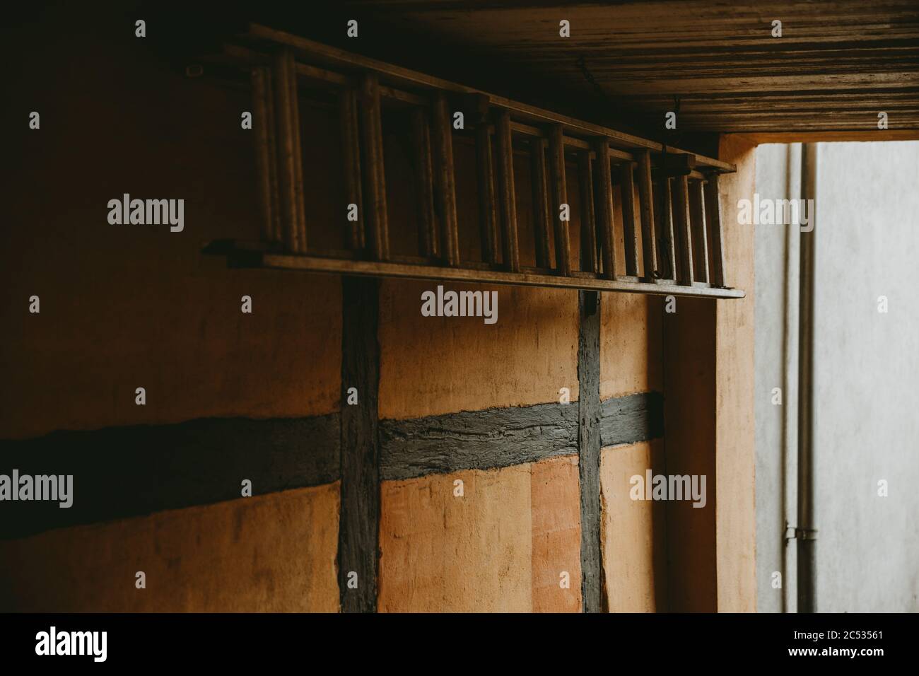 Metal ladder hanging on the orange wall with dark brown beams in the ...