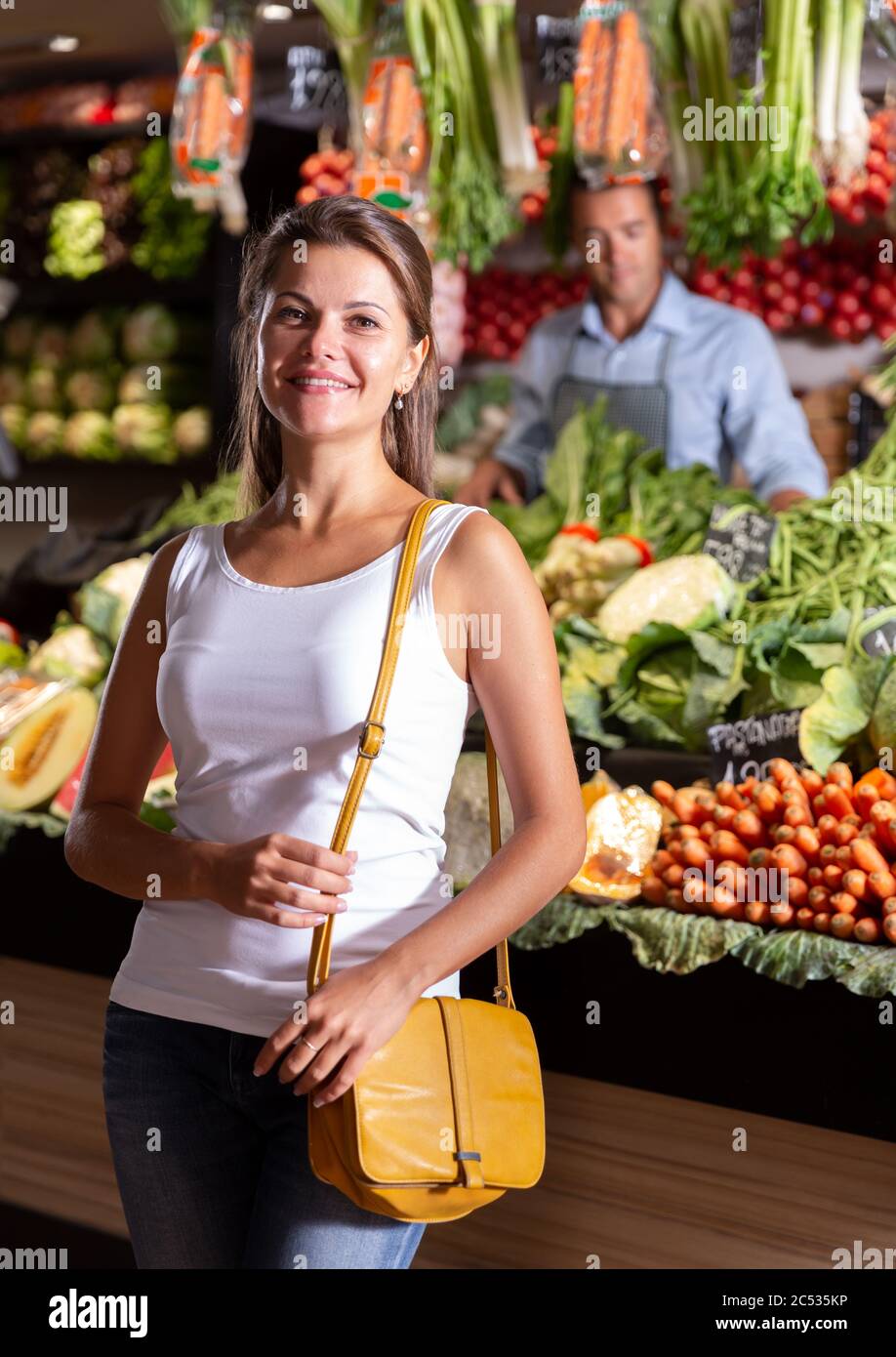 Cheerful female customer standing near counter with fresh fruits on the ...