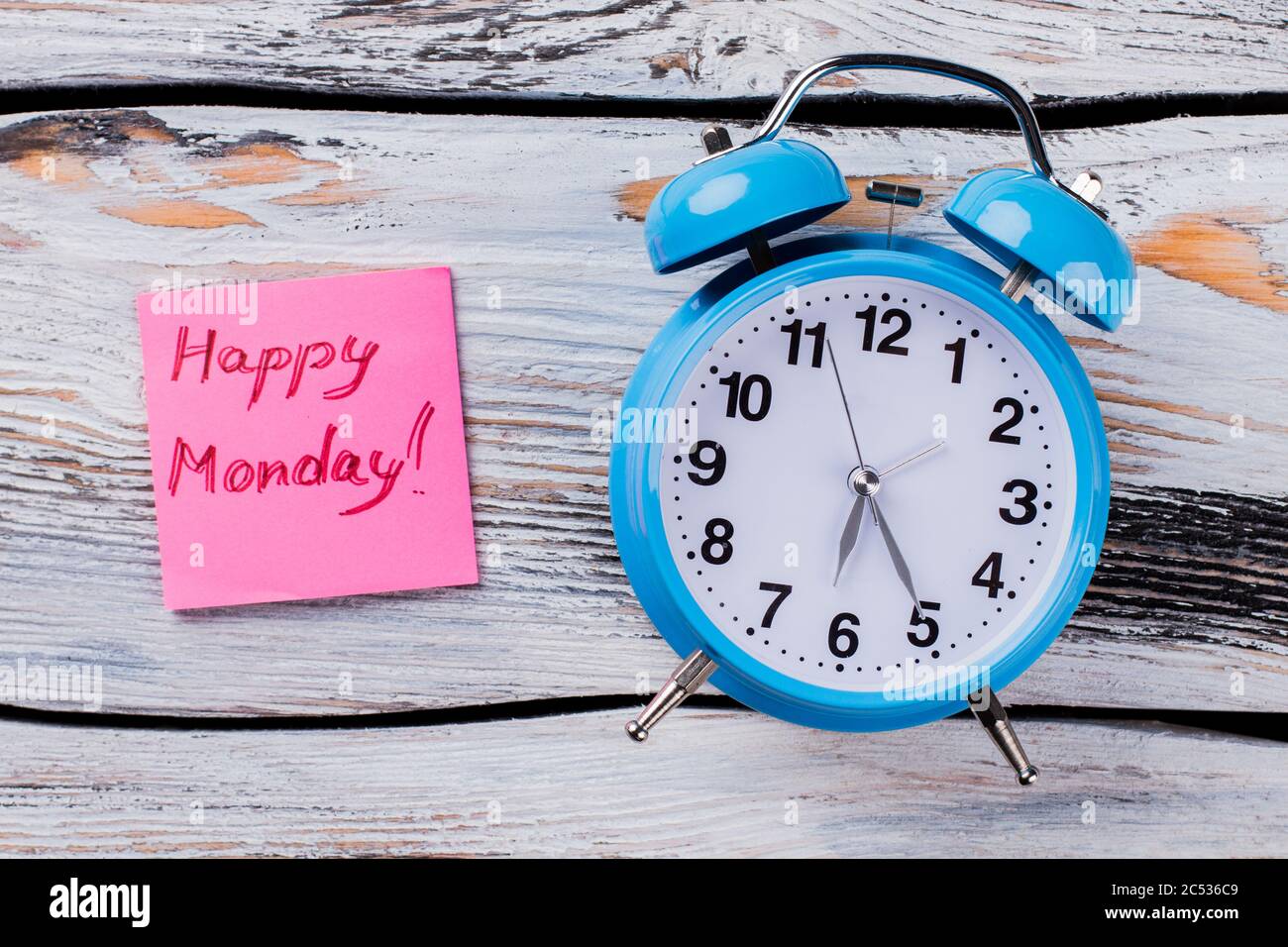 Alarm clock and paper sticker with happy monday tagline Stock Photo - Alamy