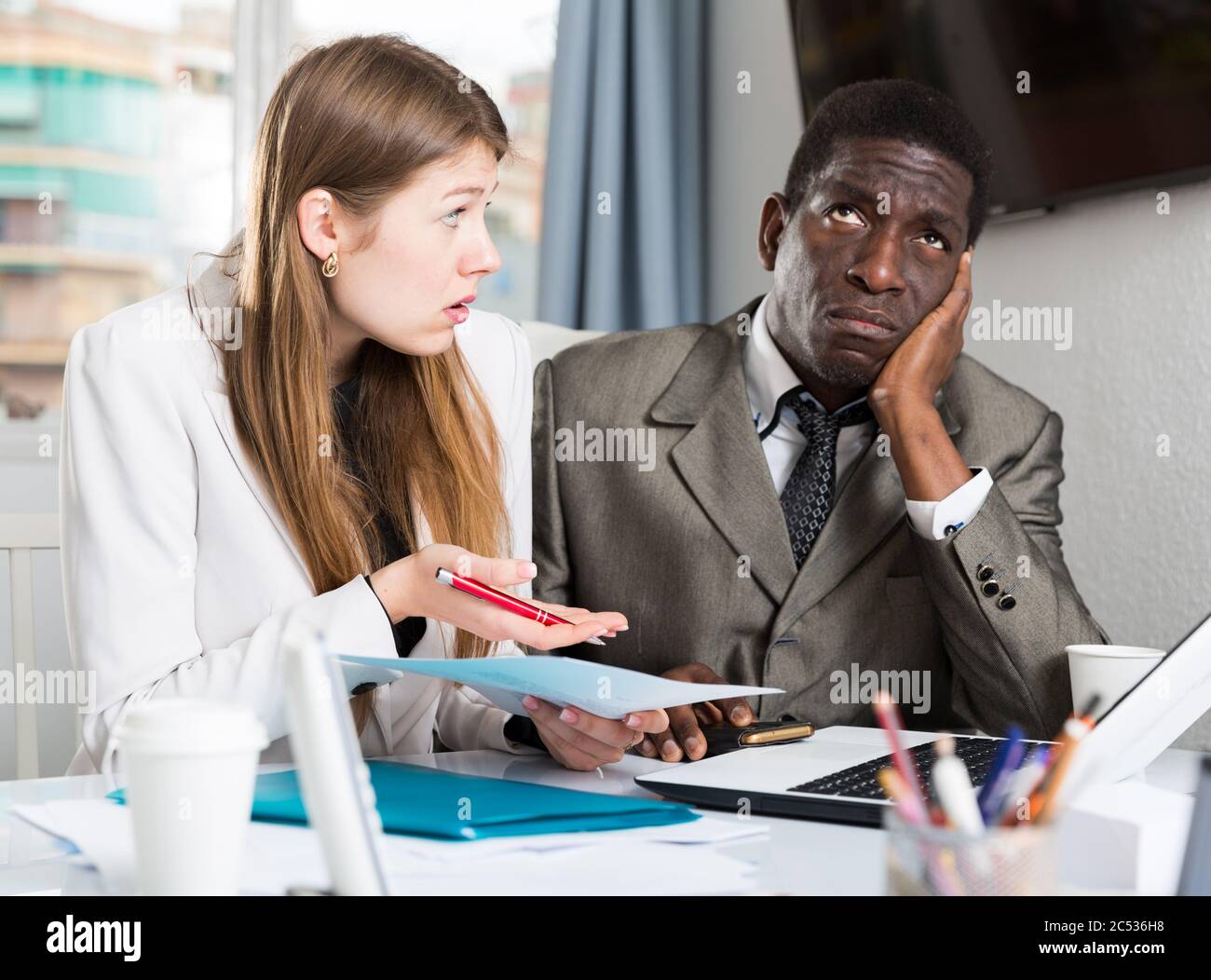 Frustrated business team working with papers and computer in modern ...