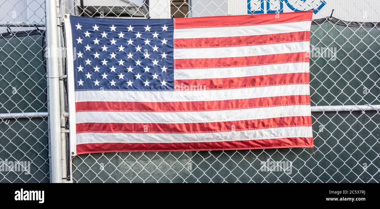 US flag attached to a chain-link fence Stock Photo - Alamy